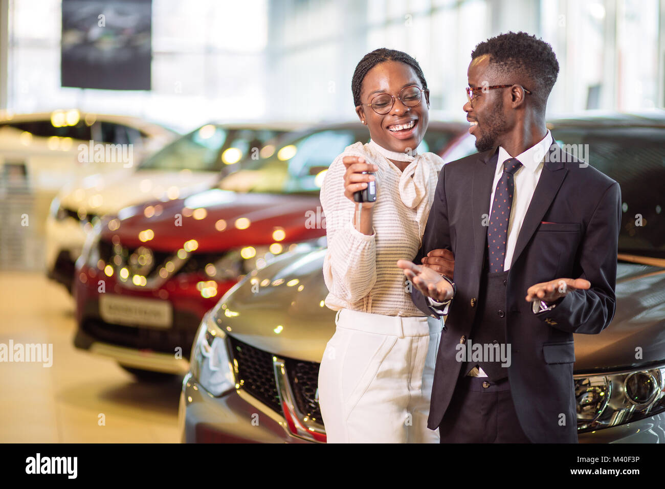 Visiting car dealership. couple holding key of their new car, looking ...