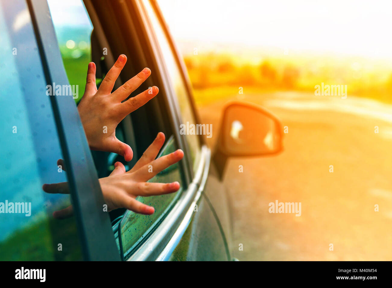 Child hands in a car window during travel to vacation. Soft light ...