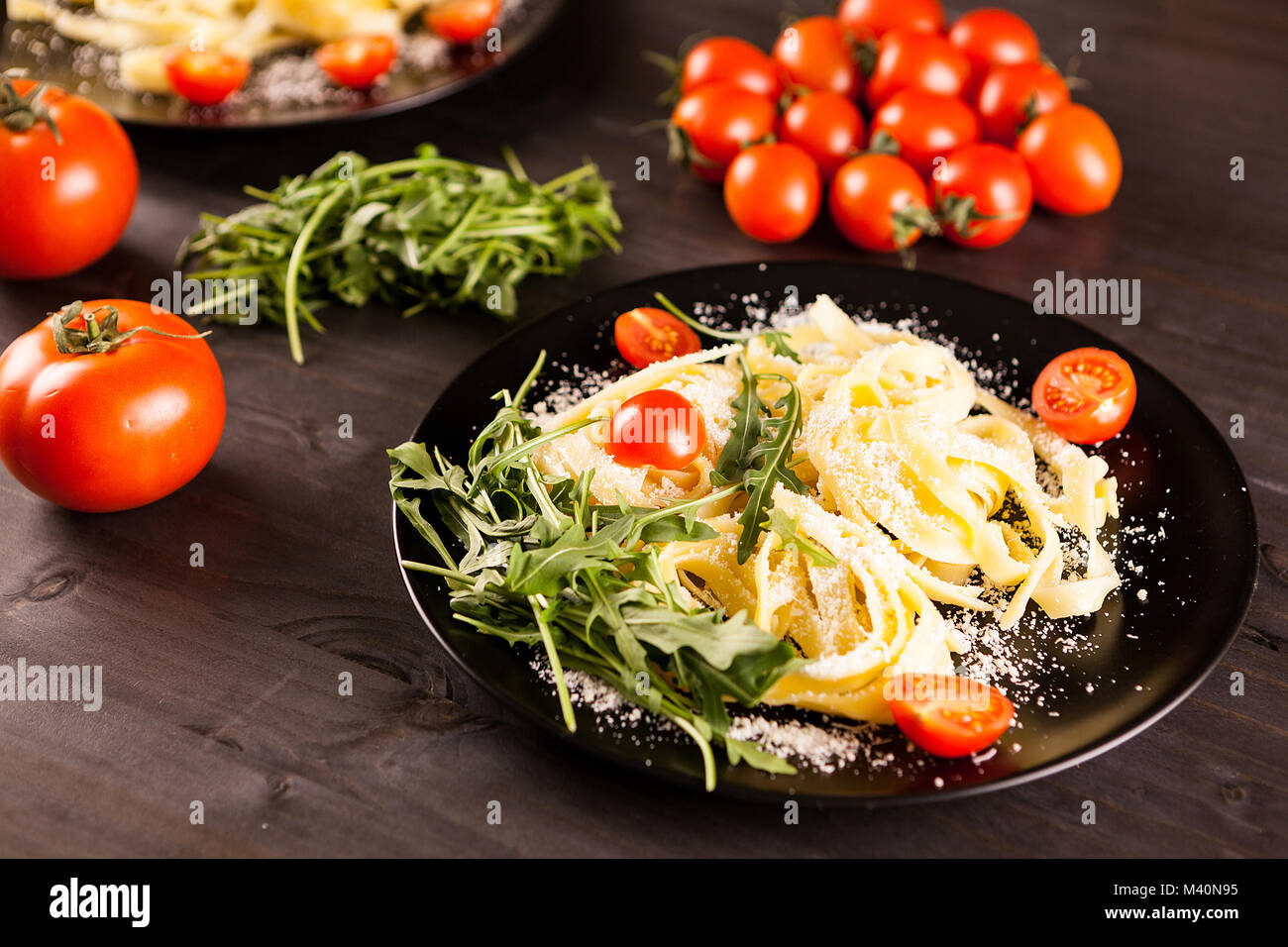 Tagliatelle pasta in black plate with parmesan Stock Photo - Alamy