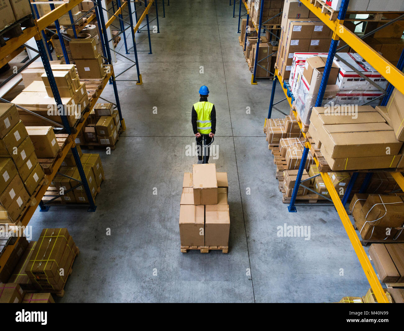 Male warehouse worker pulling a pallet truck Stock Photo - Alamy