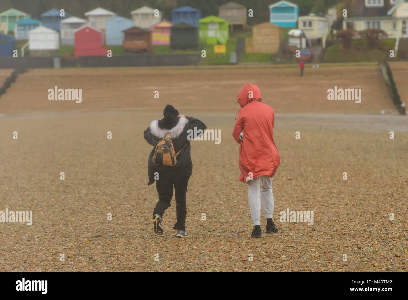 Women walking on the pebbled beach on a very windy day at Tankerton ...
