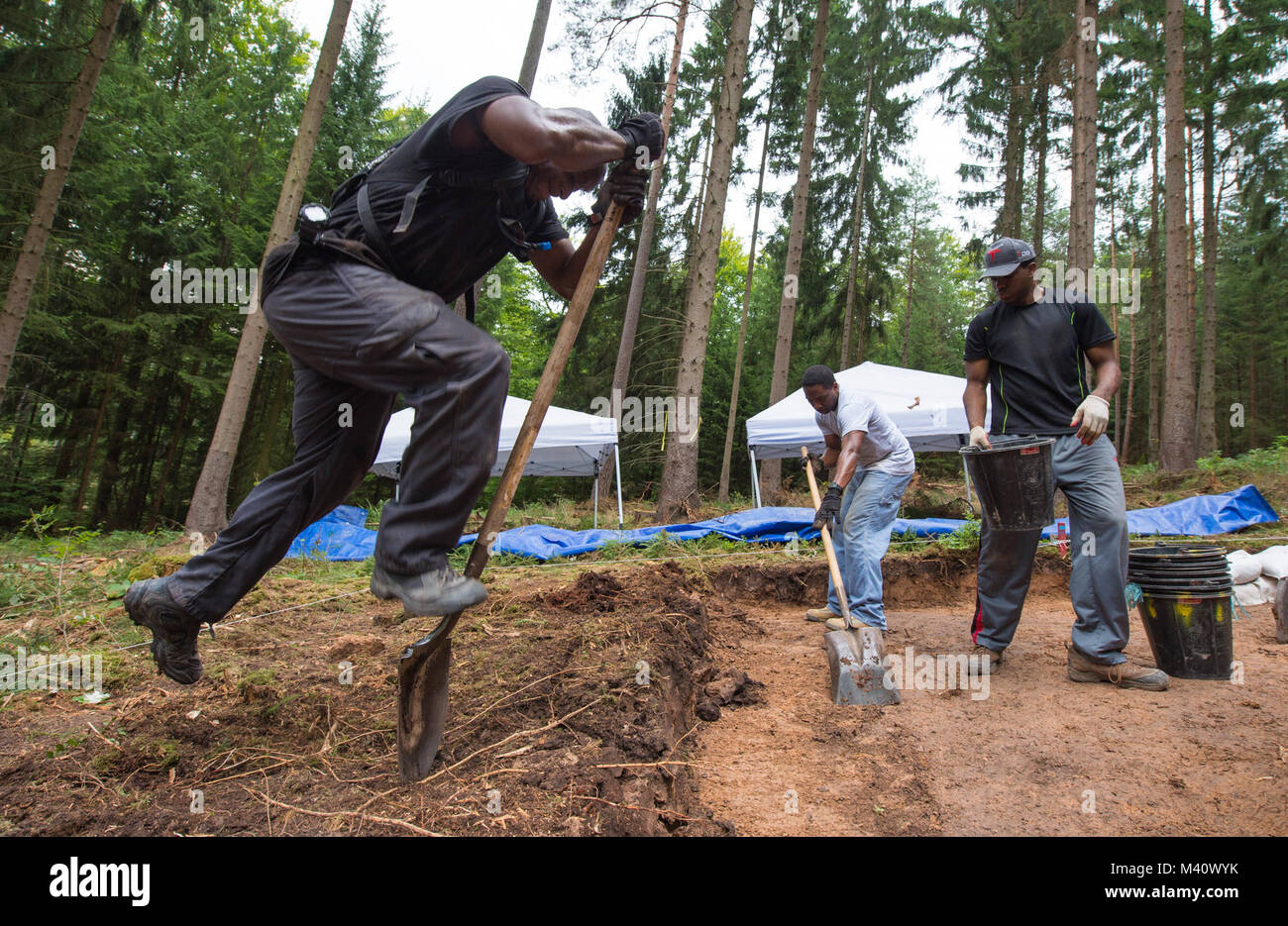 Members of a Defense POW/MIA Accounting Agency (DPAA) excavate a site ...