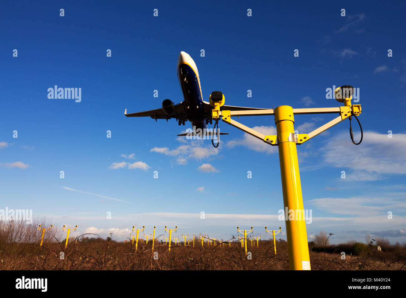 A Ryanair passenger jet flying over runway approach lighting system ...