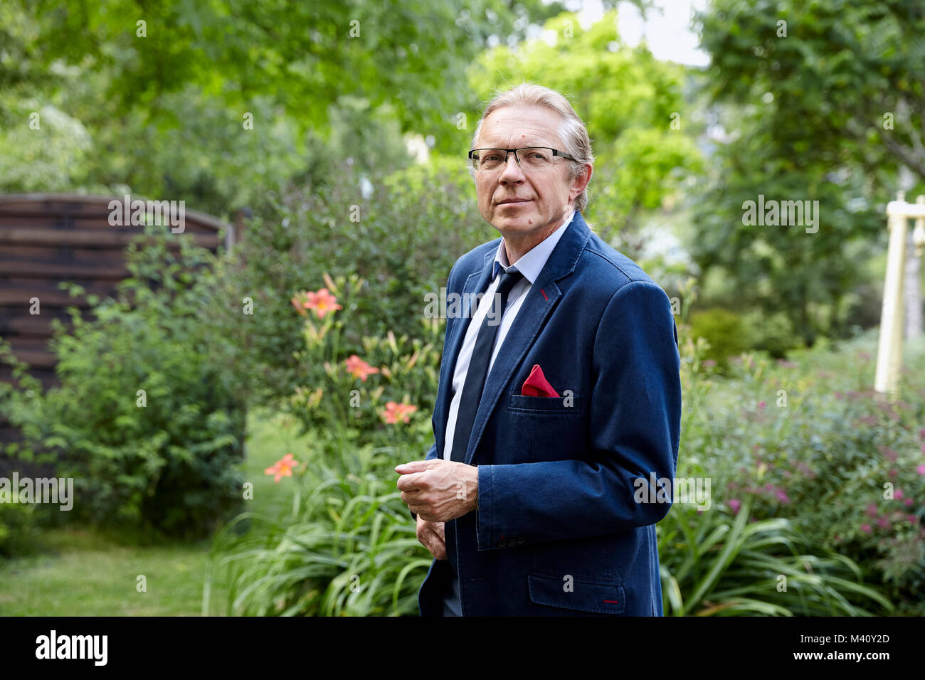 Portrait of middle-aged smiling man wearing blue jacket in the garden ...