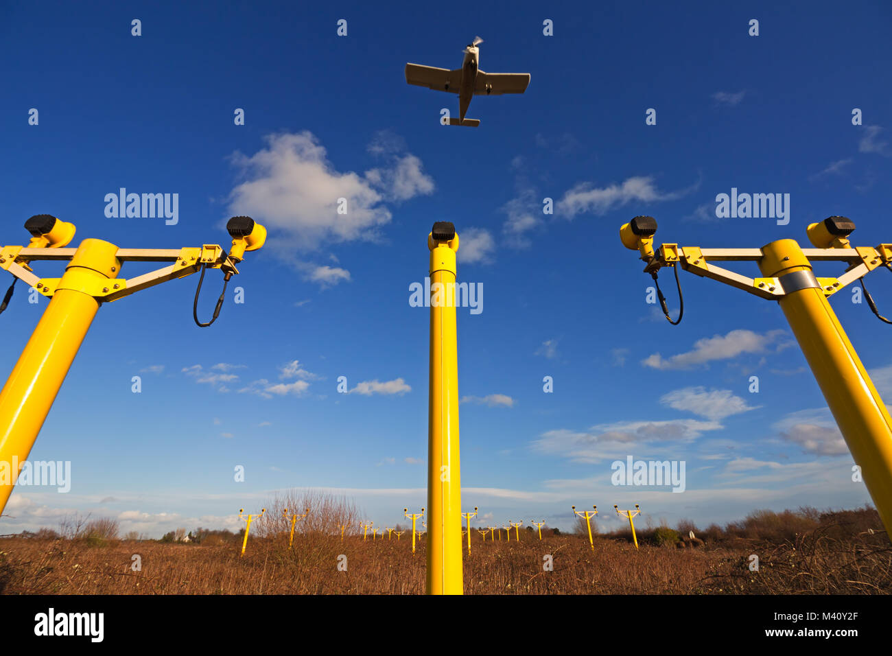 A small light airplane flying over runway approach lighting system ...