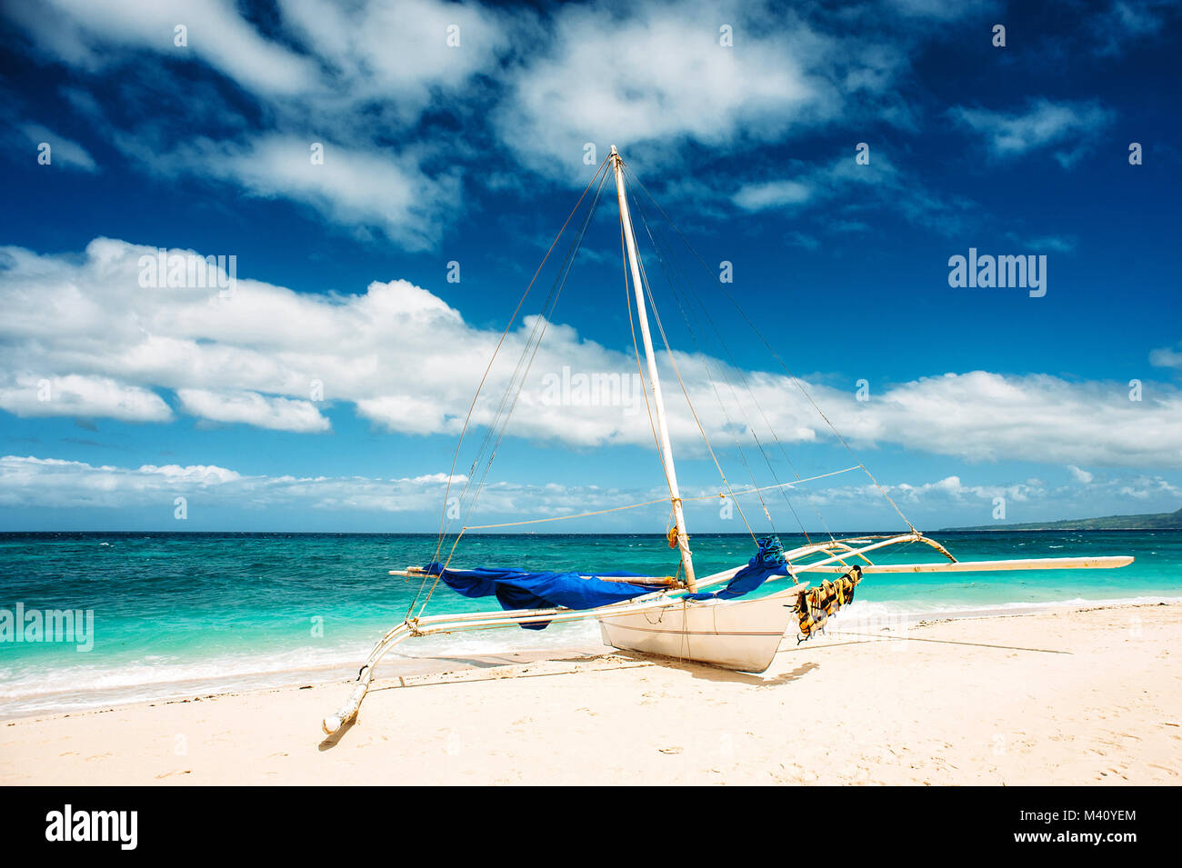 Philippine traditional boat with blue sail on the tropical beach ...