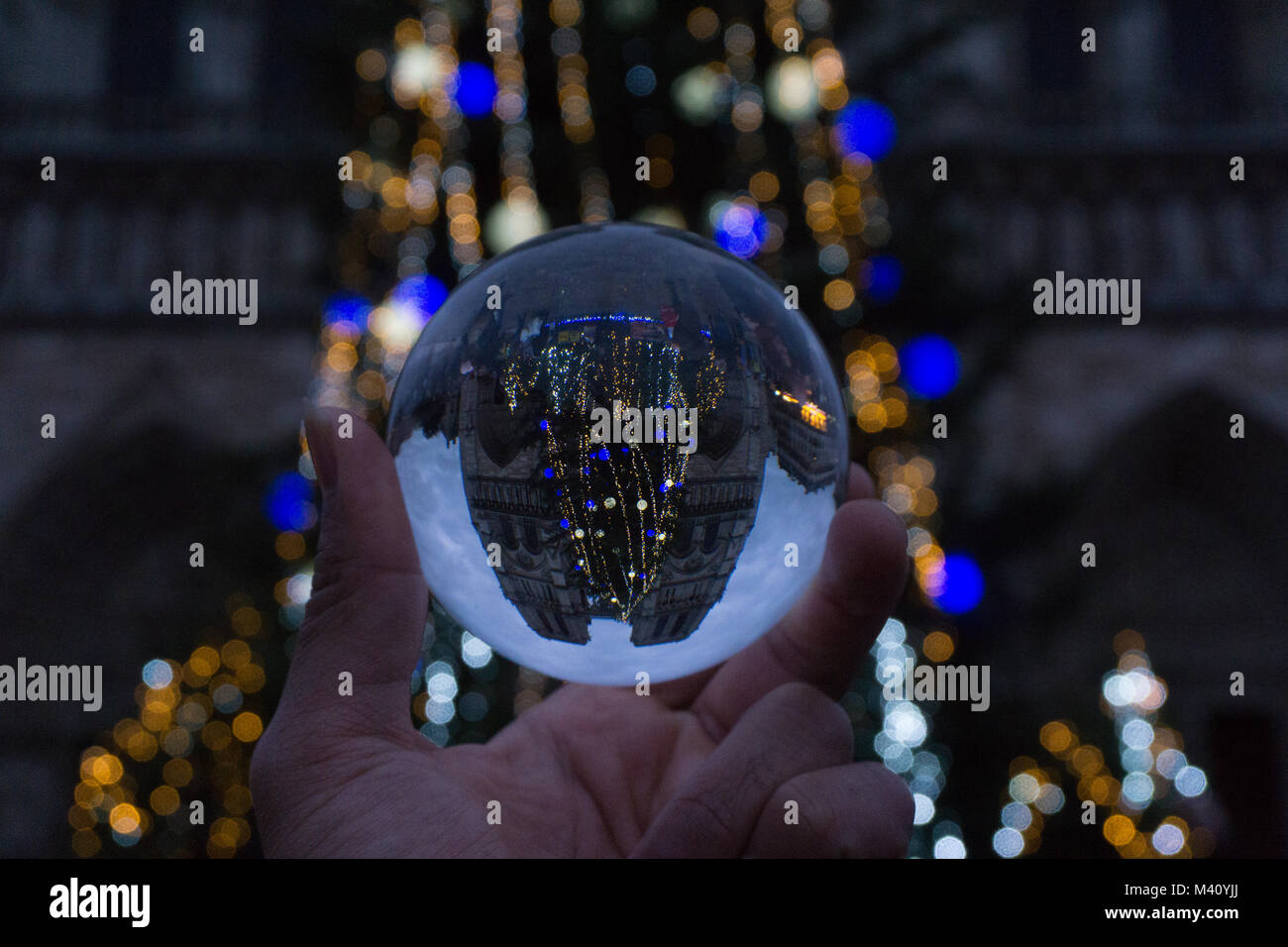A hand holding a crystal ball for optical illusion. City as the ...