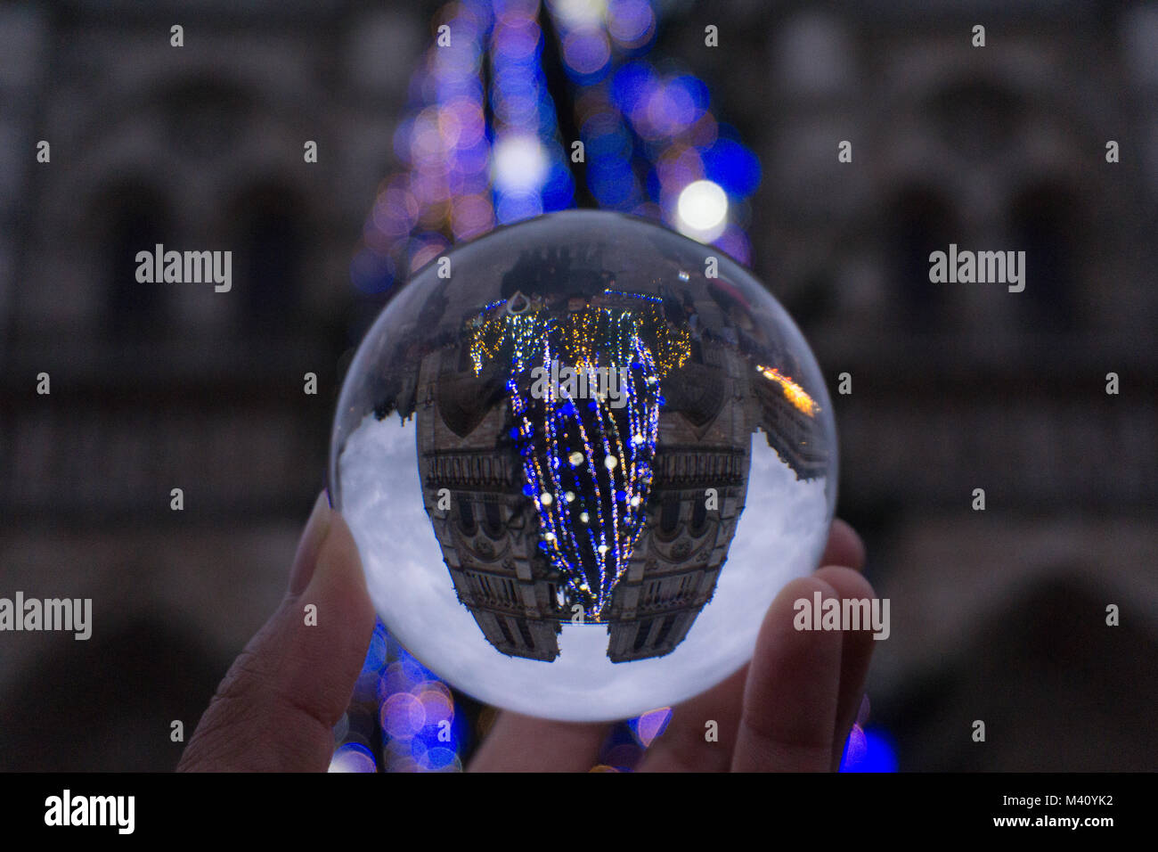 A hand holding a crystal ball for optical illusion. City as the ...