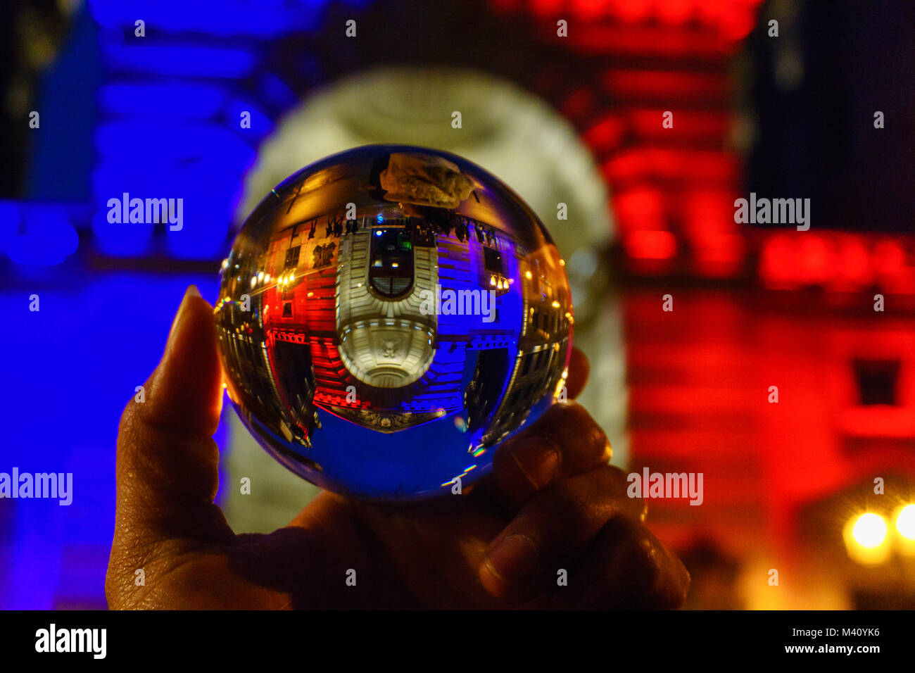 A hand holding a crystal ball for optical illusion. City as the ...