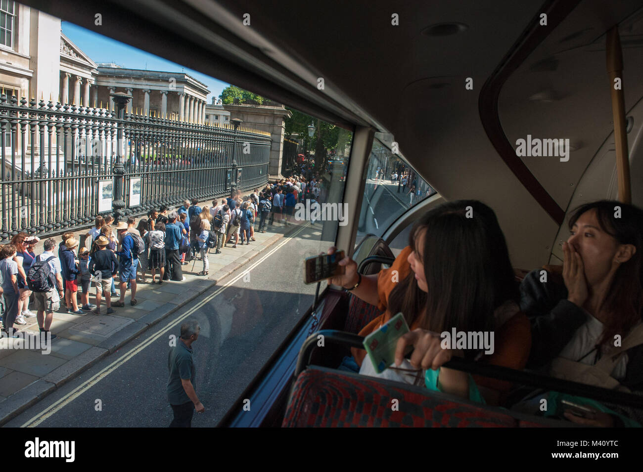 London, United Kingdom. Asian girl photographs the queue waiting to ...