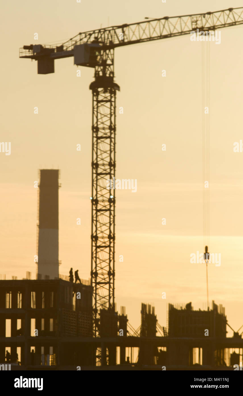 Construction side - silhouette at sunset - workers, cranes - unfinished ...