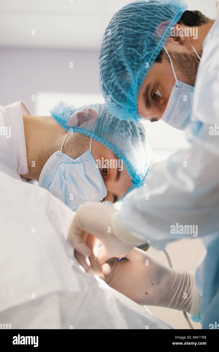 Two surgeons in blue robes make operation in surgery room Stock Photo ...