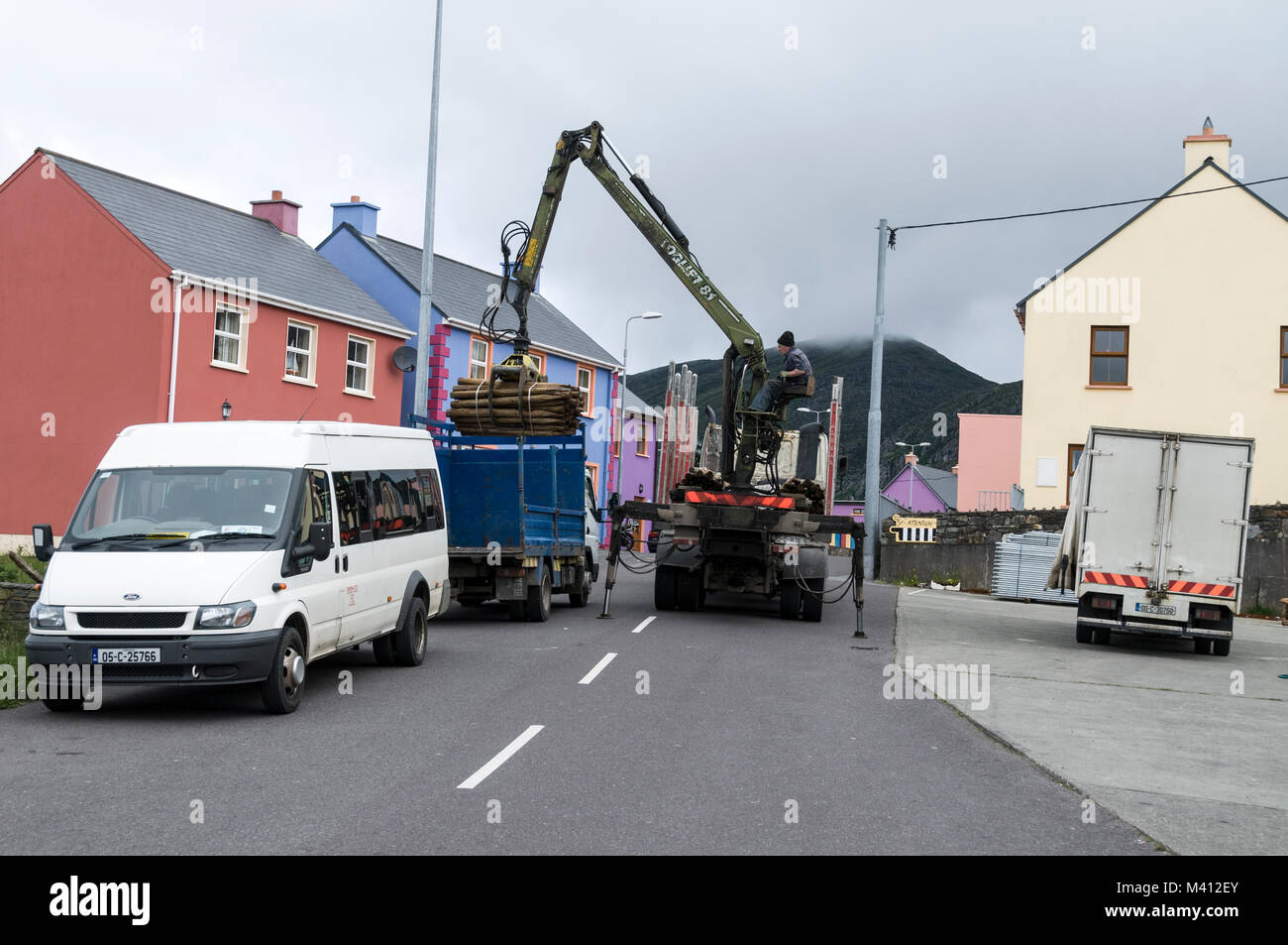 Road blocked as a lorry unloading fence poles onto a small pickup truck ...