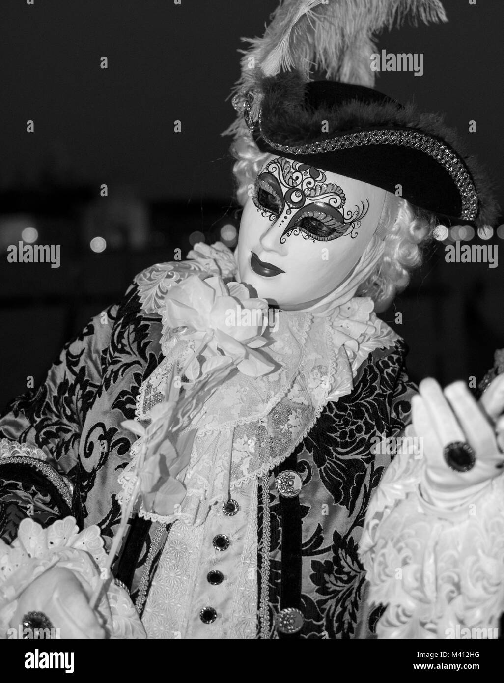 Male carnival goer in traditional costume and mask standing with back ...