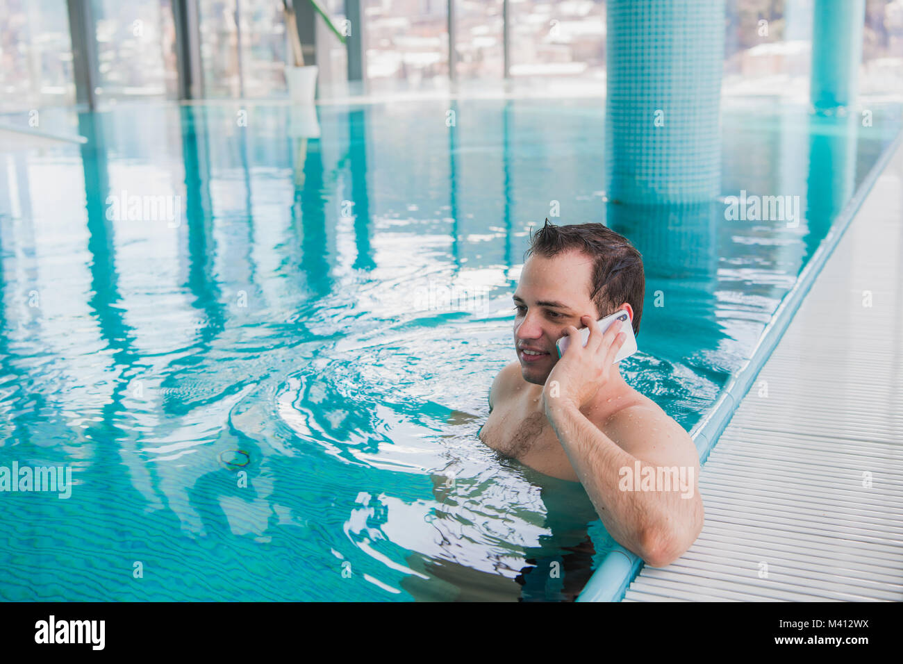 Man talking on cell phone inside the swimming pool at luxury hotel ...