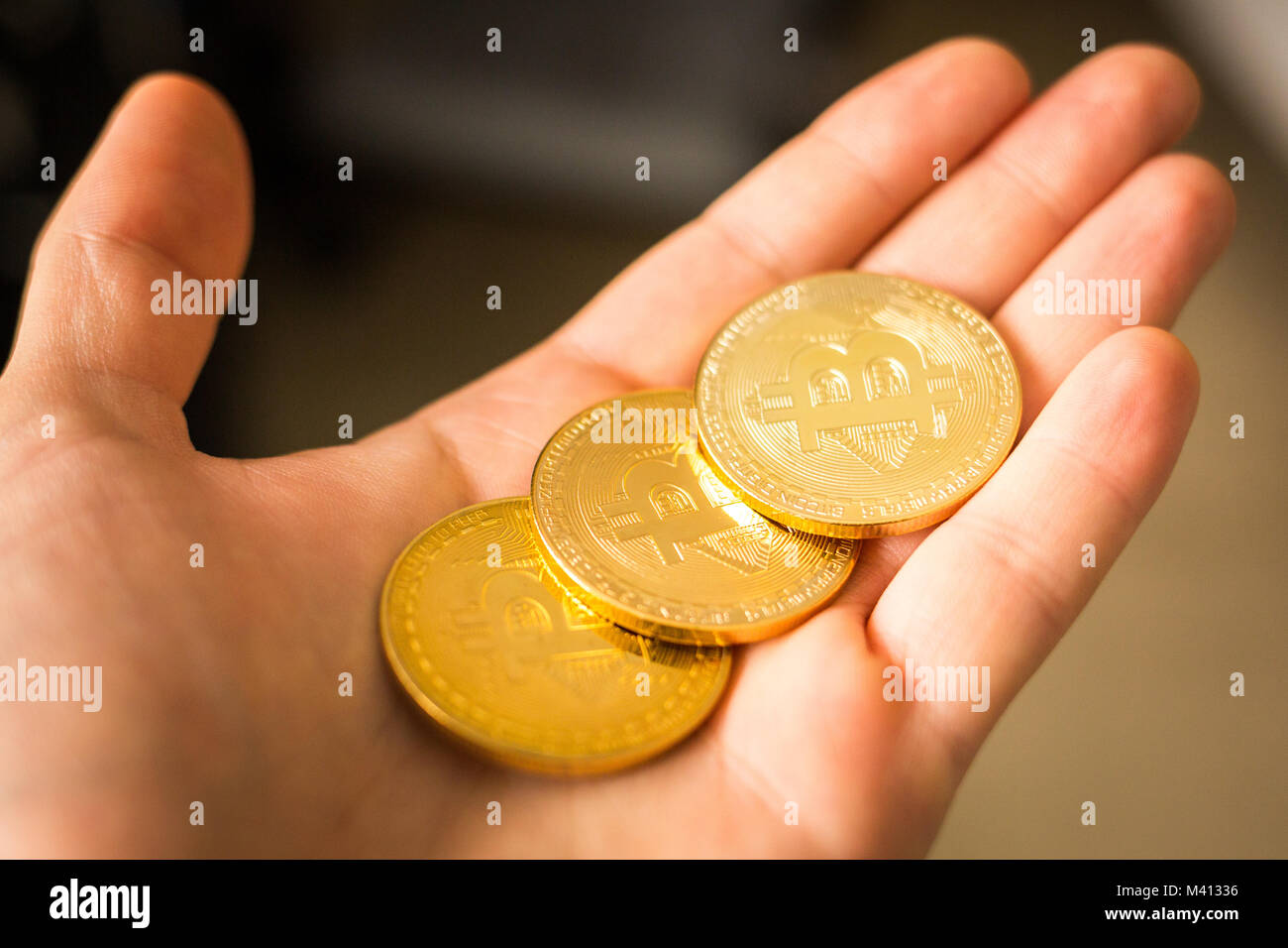 Three bitcoin coins in a hand close up gold Stock Photo - Alamy