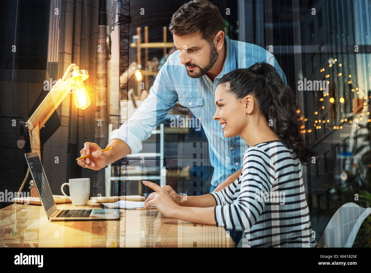 Smiling employee looking at the screen while her boss pointing to it ...