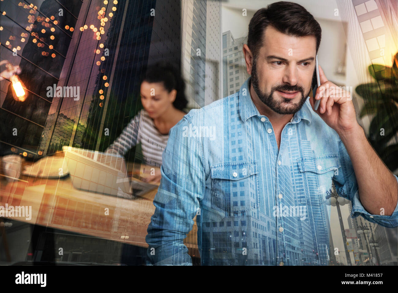Calm man having a phone talk while his colleague working Stock Photo ...