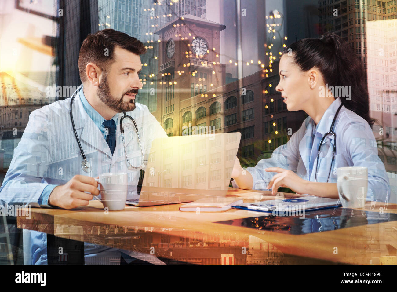 Calm doctors sitting in front of each other and talking Stock Photo - Alamy