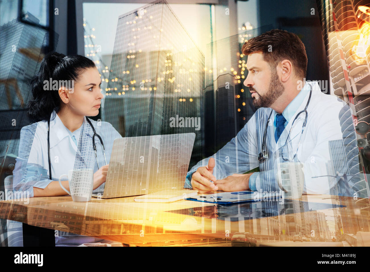 Serious smart doctors looking at each other while having an important ...