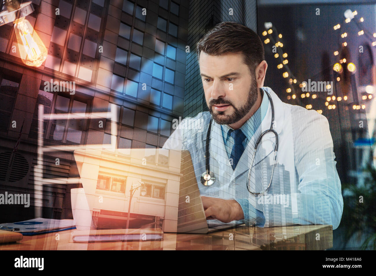 Experienced doctor looking at the screen of a laptop while being at ...