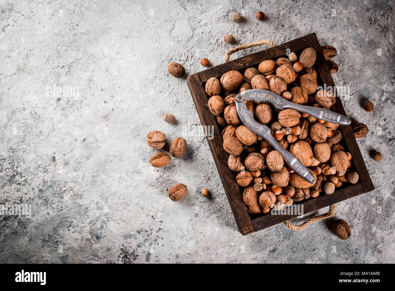 Various nuts and nutcracker in wooden box. On rustic grey stone table ...
