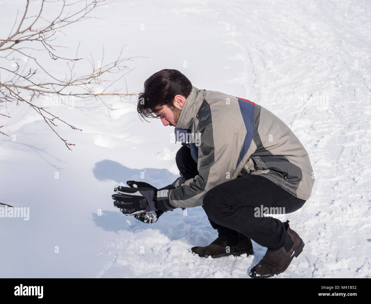 Cheerful handsome man in outerwear throwing snowball posing at camera ...