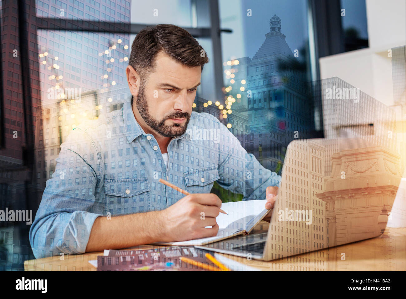 Concentrated employee frowning while making notes Stock Photo - Alamy