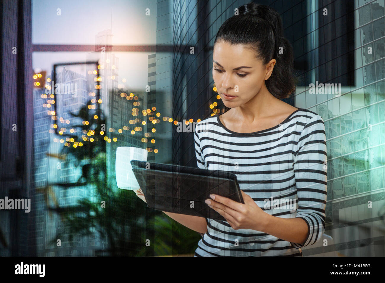 Curious woman looking at the tablet and feeling interested Stock Photo ...