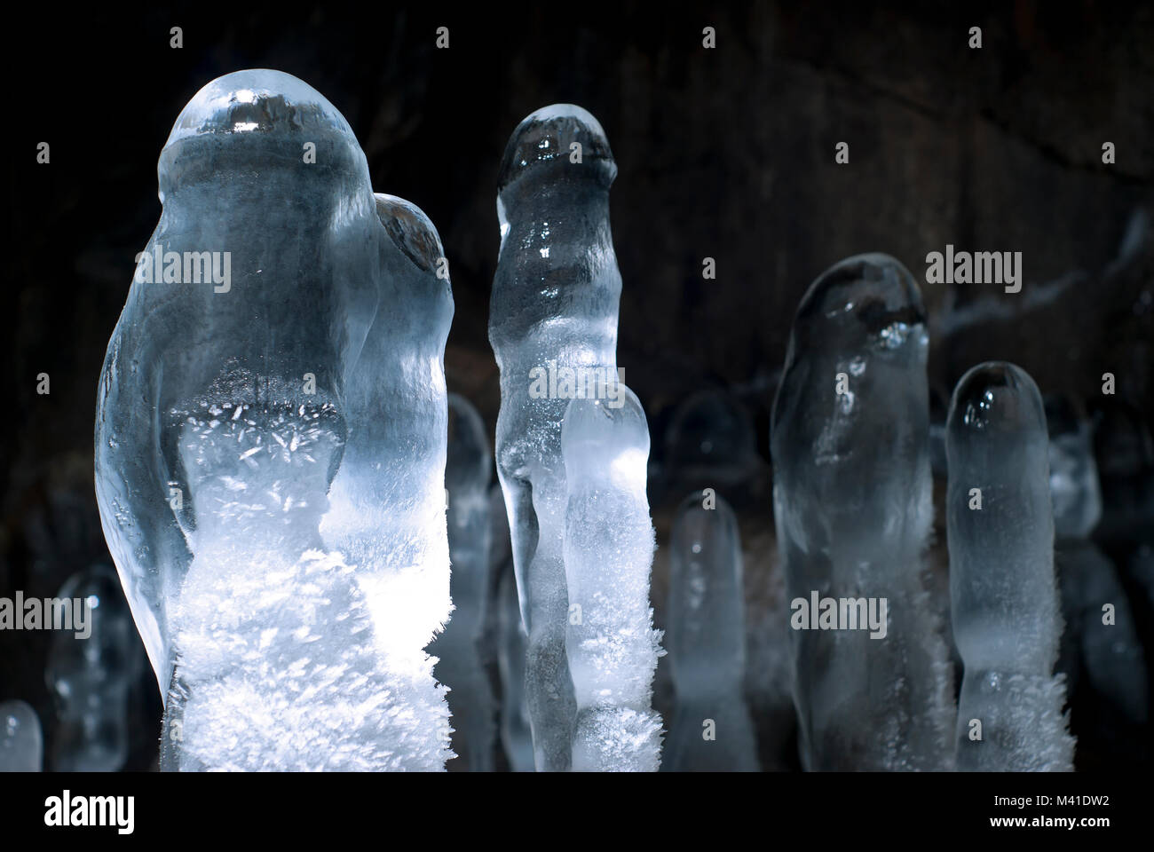 group of transparent ice stalagmites in a cave closeup on a dark ...
