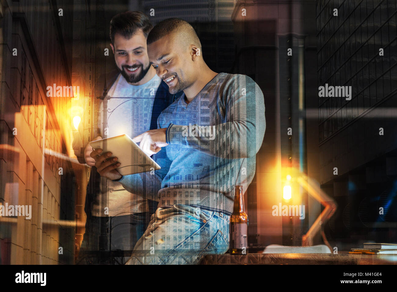 Smiling man pointing to the screen while showing a photo to his friend ...