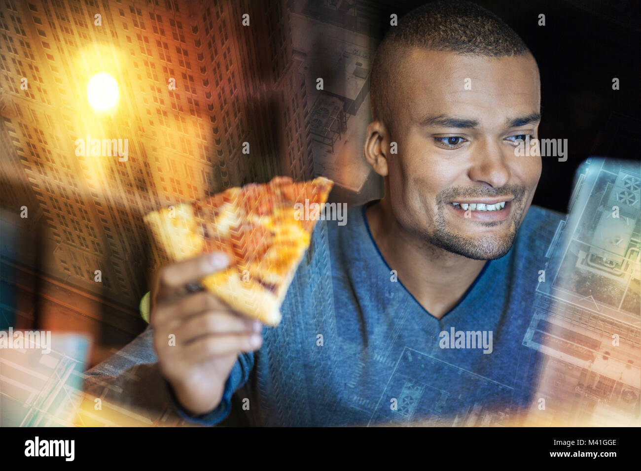Emotional man eating pizza and smiling while looking at his laptop ...