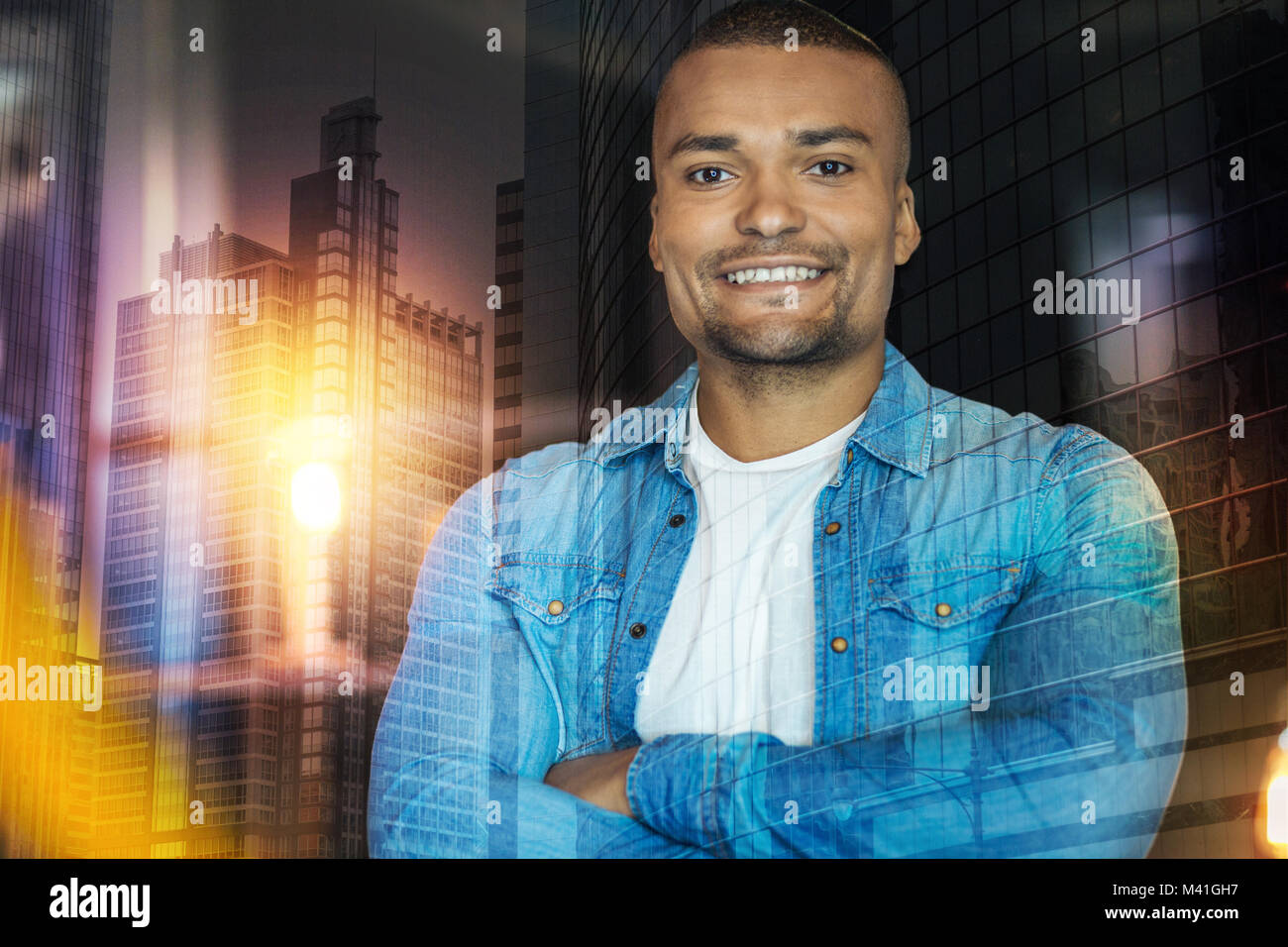 Smart young man smiling and crossing his arms Stock Photo - Alamy