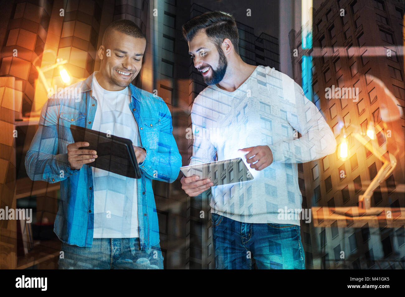 Positive friends looking excited while comparing their amazing gadgets ...