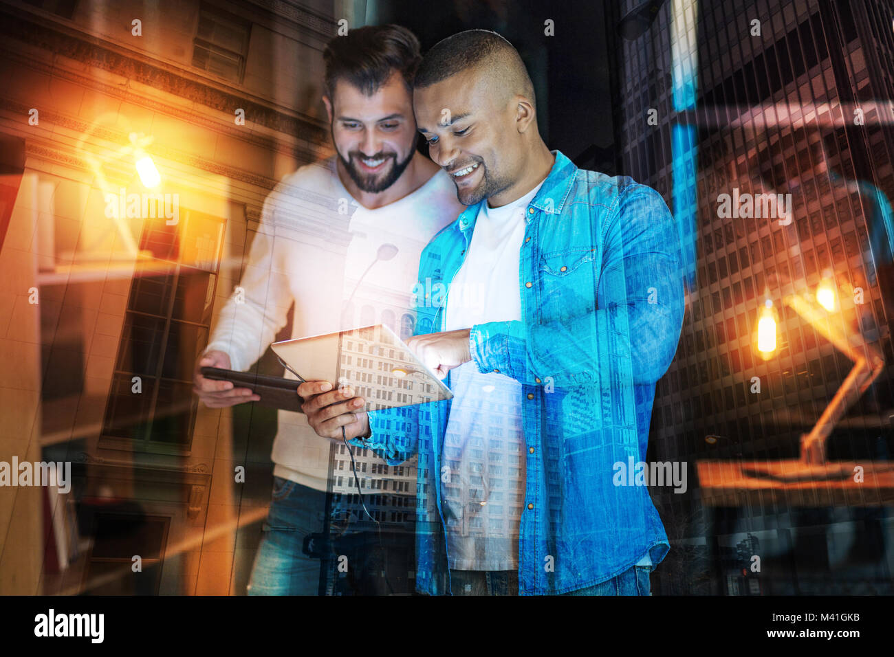 Two friendly people holding their modern tablets and smiling cheerfully ...