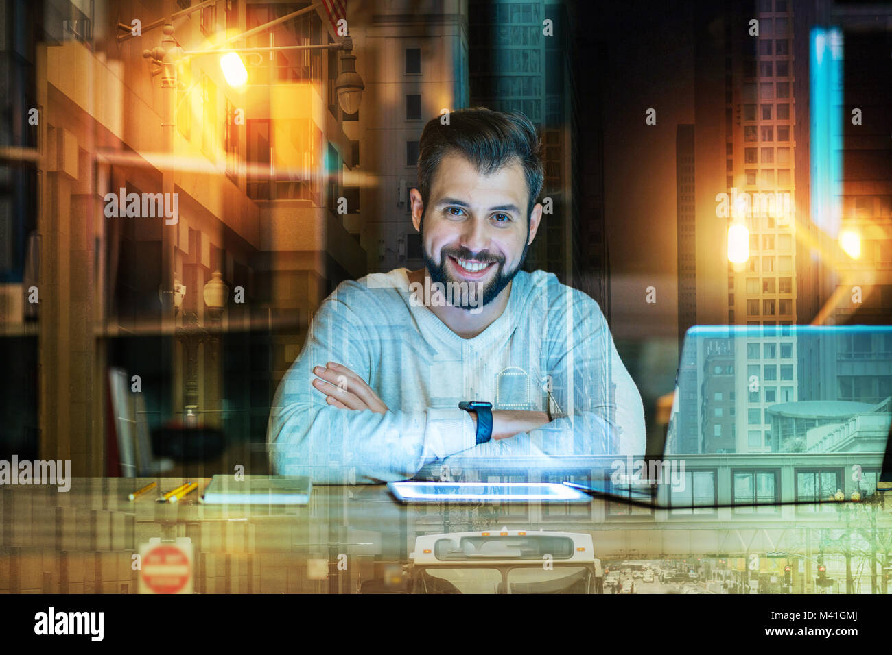 Smart man smiling while sitting at the table after his working day ...