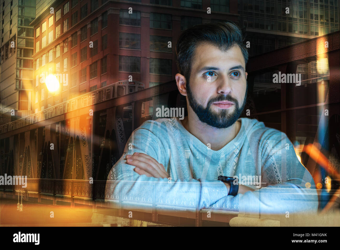Calm young man sitting alone and thoughtfully looking into the distance ...