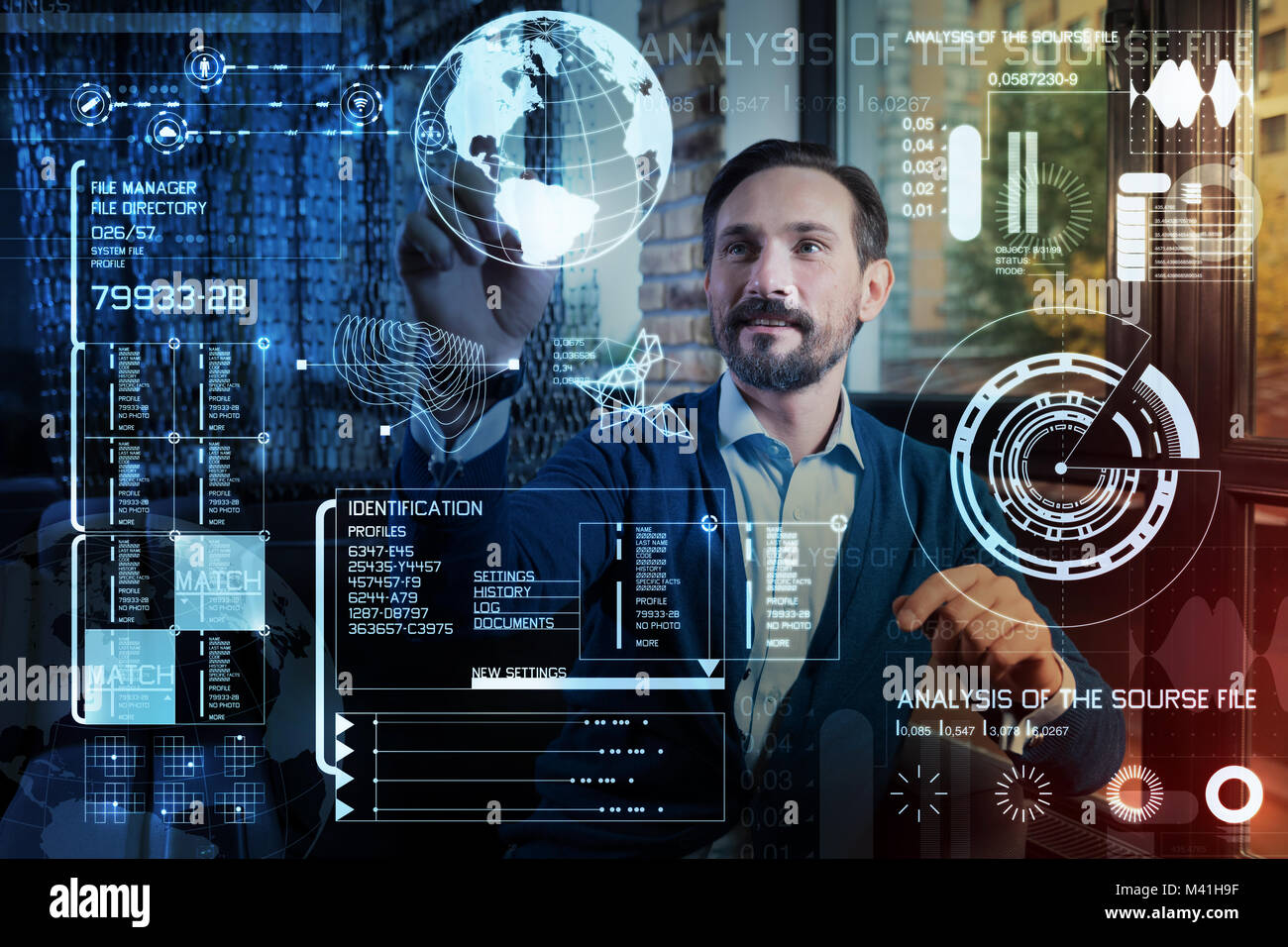 Cheerful programmer standing in front of a screen and looking satisfied ...