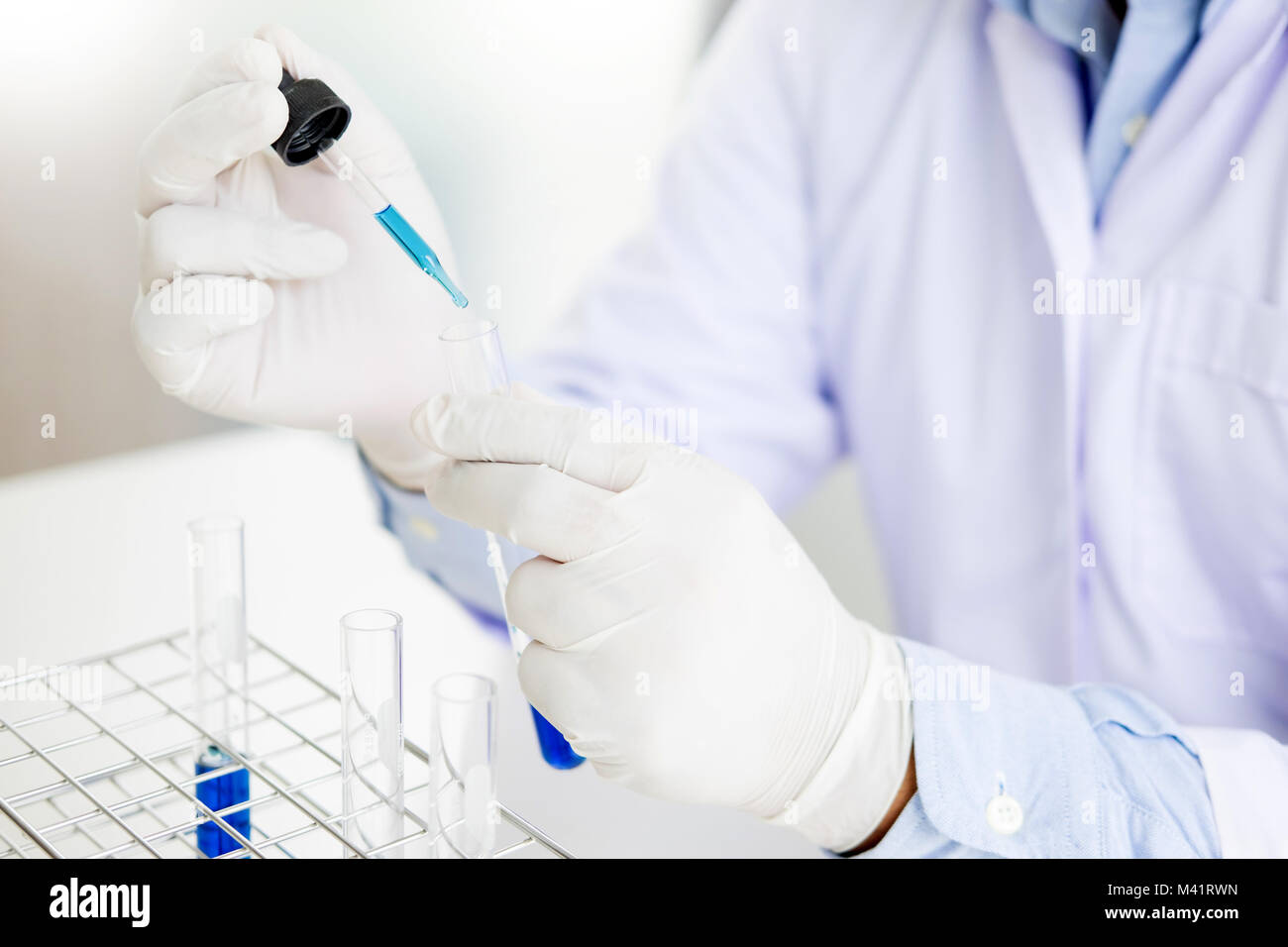 Scientist dropping adds the reagent from the dropper to test tube ...