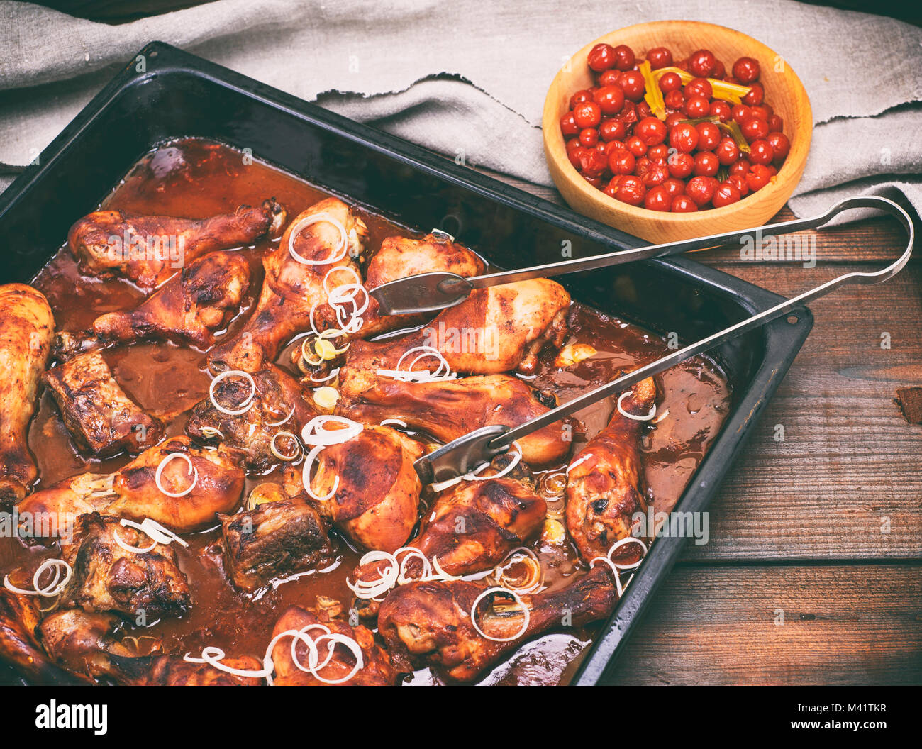 fried chicken legs with crispy crust in honey tomato sauce on a black ...