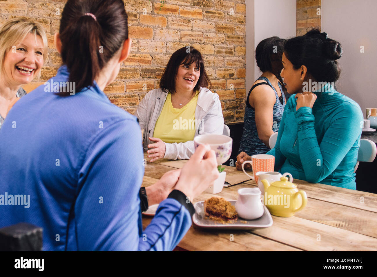 Women are sitting at a table in a cafe, socialising over tea and cake ...
