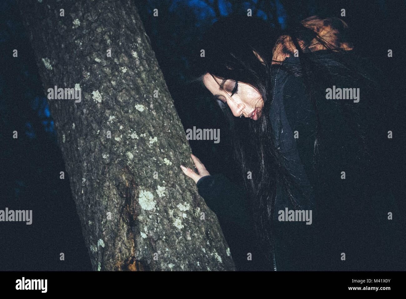 girl holding onto a tree in the forest at night Stock Photo - Alamy