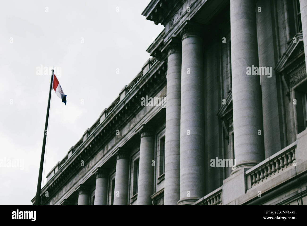 Building with a flag outside lined with columns Stock Photo - Alamy