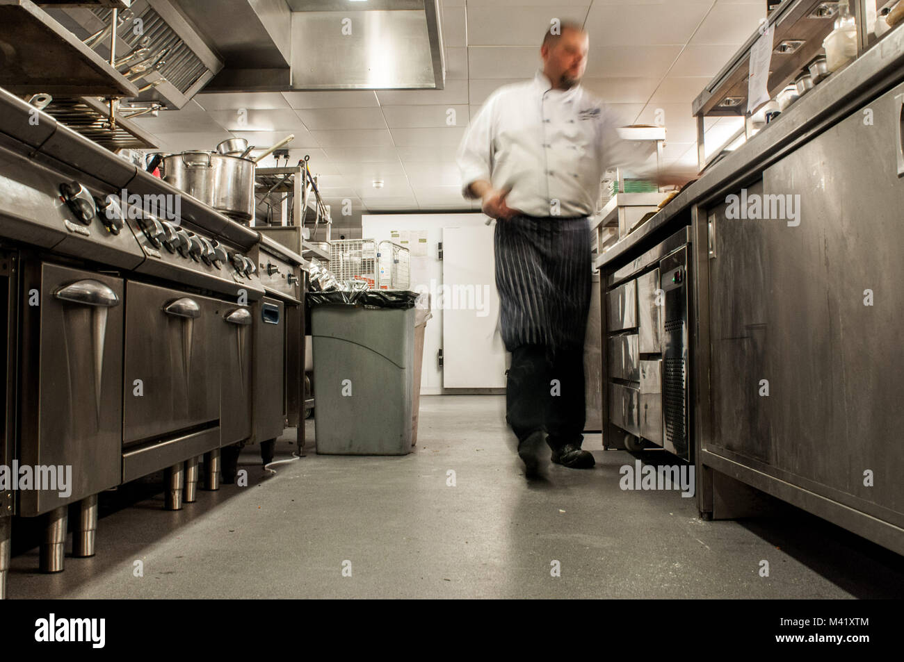A photo with motion blur of a chef moving quickly in a restaurant ...