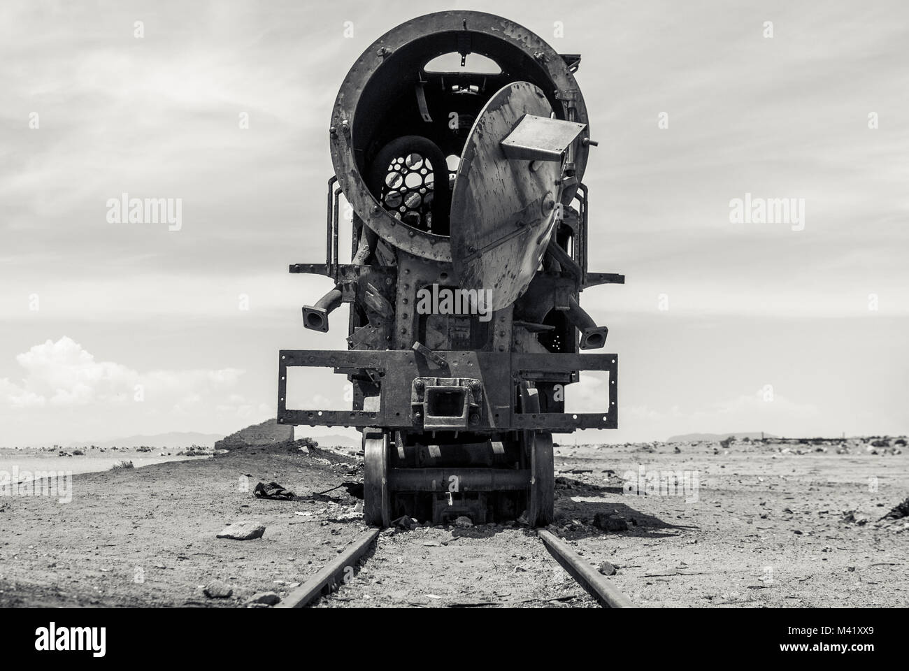An black and white photo of an abandoned old train engine sitting on tracks in the high Andean ...