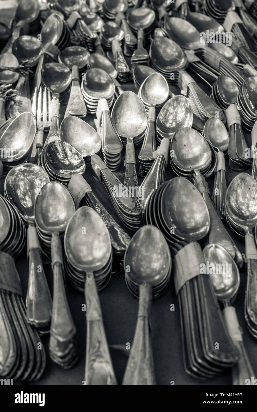 A photo of lots of spoons and cutlery arranged in a pattern on a market ...