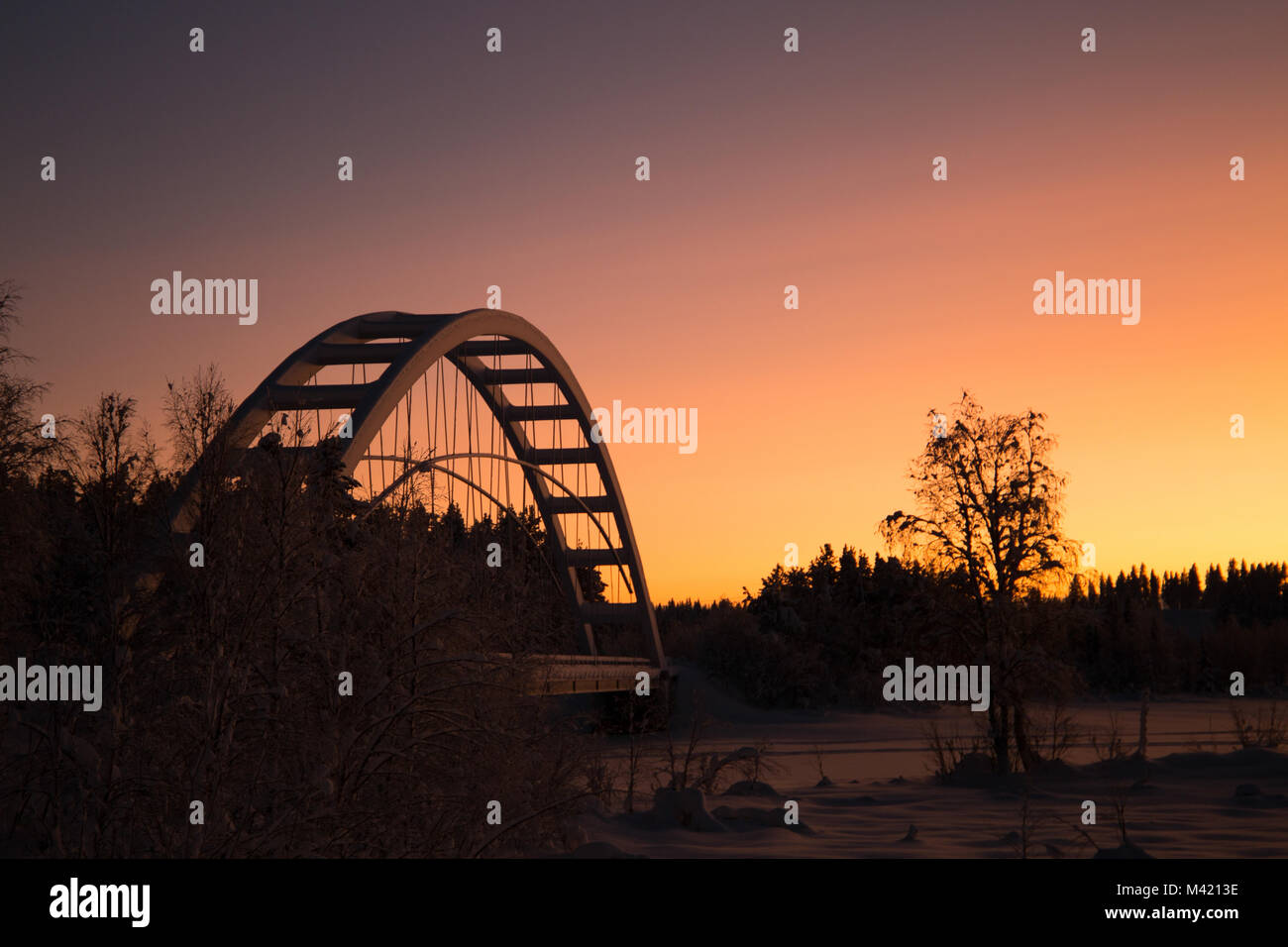 Bridge over the frozen Kalix river coved in snow at sunset ...