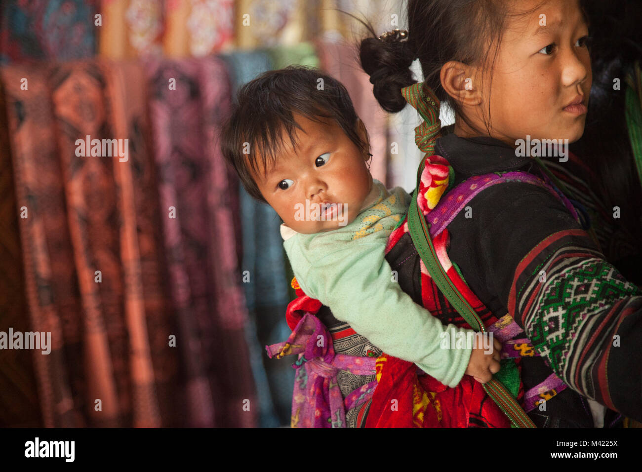Young Hmong native girl carrying her sibling on her back Sapa Vietnam ...