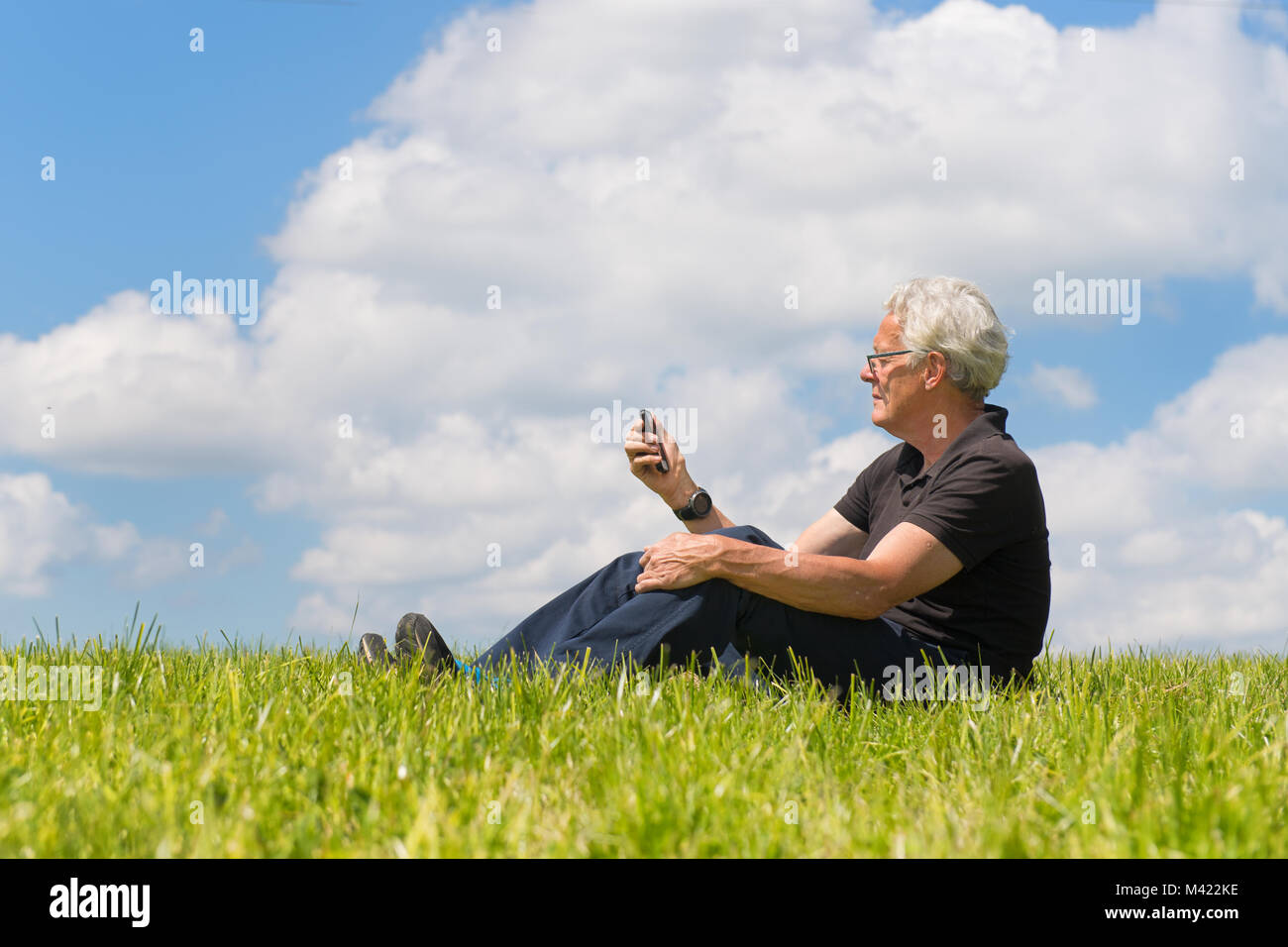 Senior man sitting in nature with mobile phone Stock Photo - Alamy