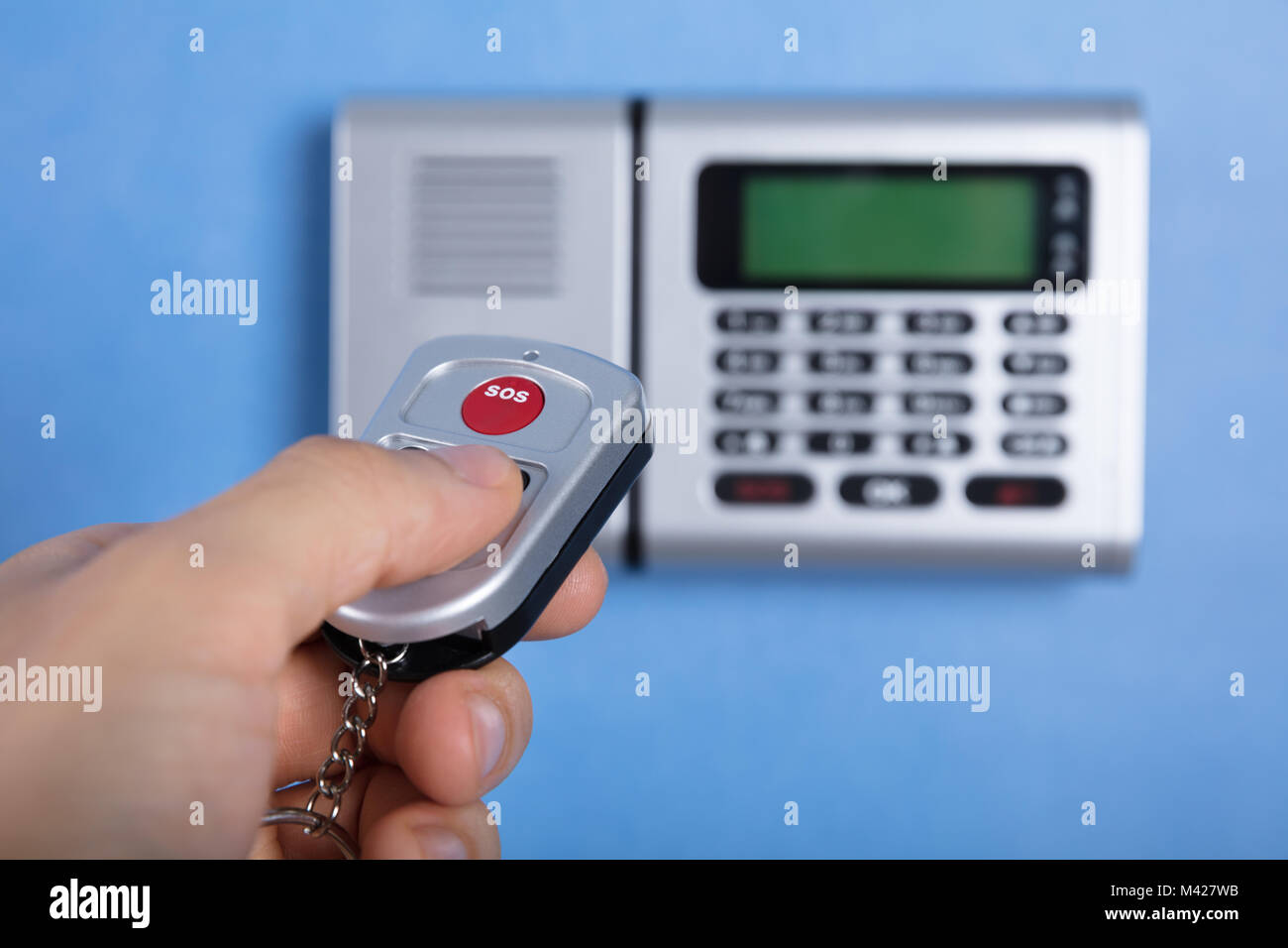 Close-up Of Person Hand Using Remote Control In Front Of Security Alarm ...